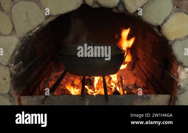 Cooking food in the oven on an open fire. Cast-iron cauldrons with food ...
