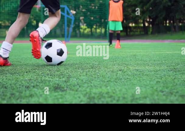 Close up of boys feet in football shoes which working out the kick with ...