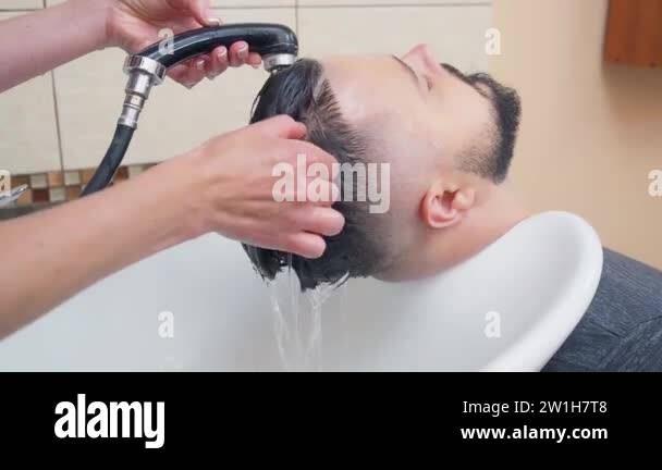 Head washing after haircutting, close shot. Stylist washing clients ...