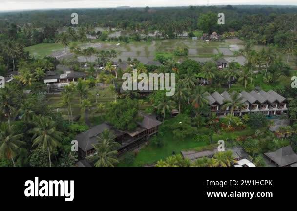 Zooming back Aerial view of luxury hotel with straw roof villas and pools in tropical jungle and ...
