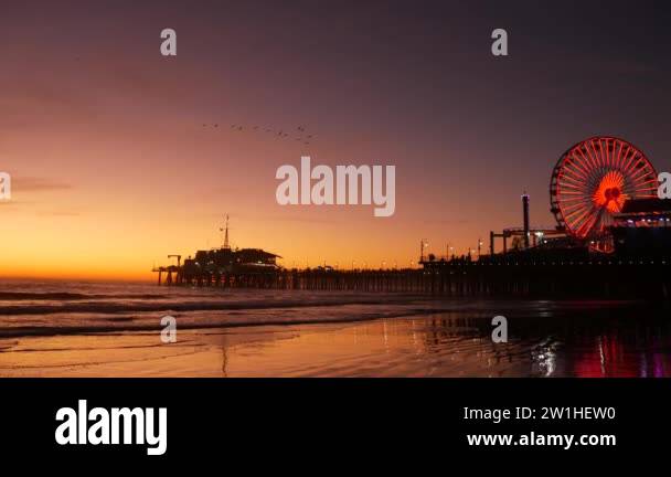 Twilight waves against classic illuminated ferris wheel, amusement park ...