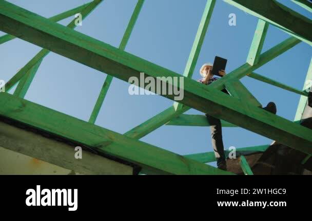 A female architect is working with a tablet among the rafters of the ...