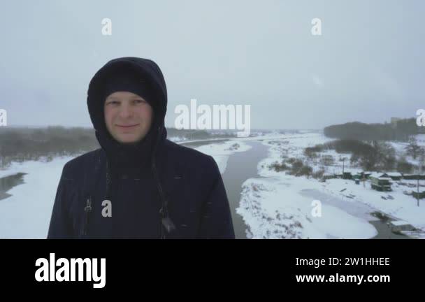 Smiling man in the hood is in winter snowfall. Cold weather. Immunity ...