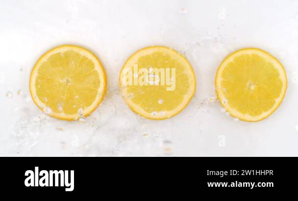 Three fresh lemon, top view of water flowing on a white background ...
