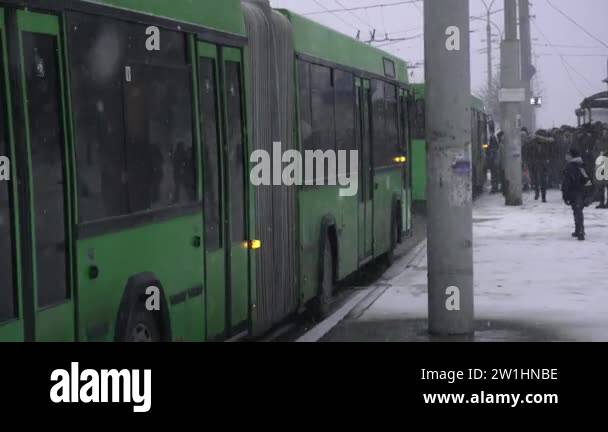 Public transport buses arrive at the bus stop during winter snowfall in ...
