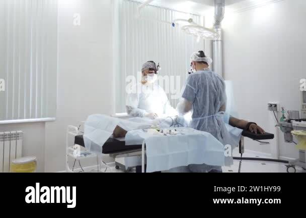 Two male surgeons at the work with time lapse effect. Action. Sedated ...