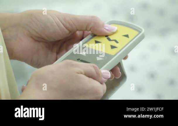 Women 's hand presses buttons on remote to adjust hospital bed position ...