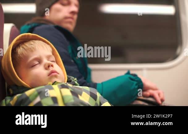 A boy rides the subway with dad. A boy sitting on a seat is sleeping ...