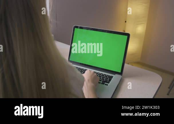 Green screen on a laptop. A young girl types a message or searches ...