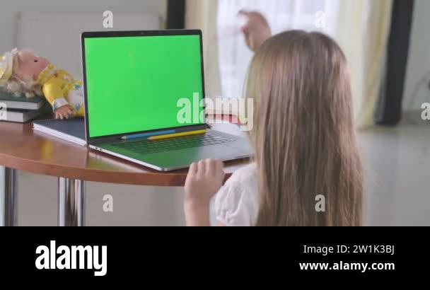 Back view of Caucasian girl looking at laptop with green screen ...