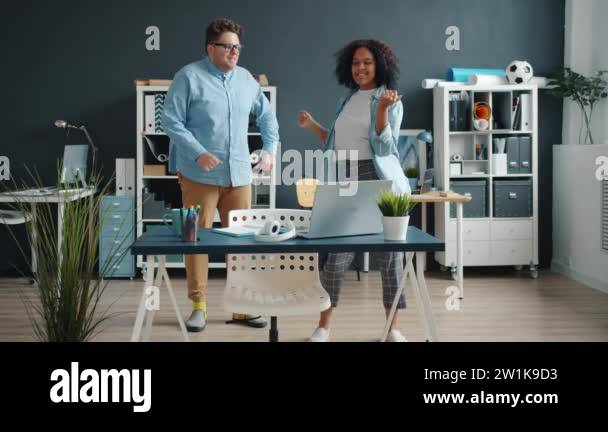 Office workers young man and woman dancing in workplace having fun ...