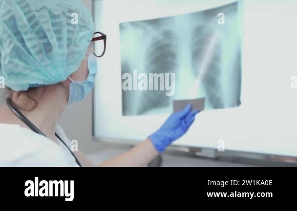 Woman doctor sitting at desk, working on computer, holding X-ray of ...