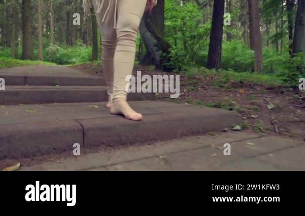 Barefoot beautiful female feet are walking on a stone step. Around the ...