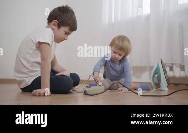 dangerous games, curious little boys plugging power plug from the iron ...