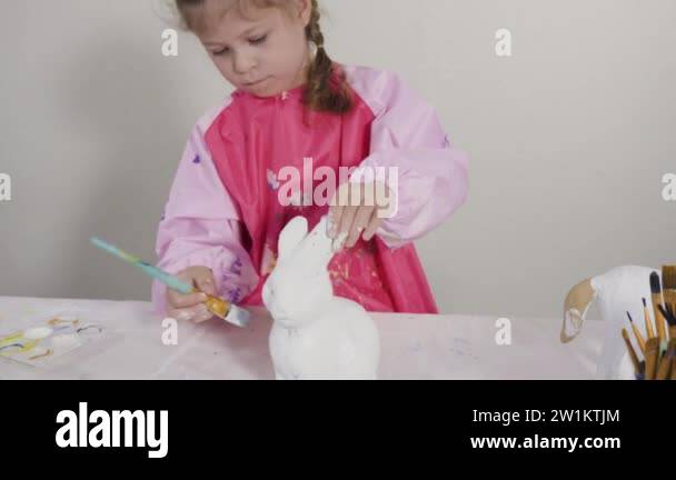 Little girl painting paper mache figurines with acrylic paint for her ...