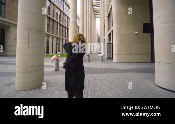 Woman takes pictures of bank building. Action. Woman photographer walks ...
