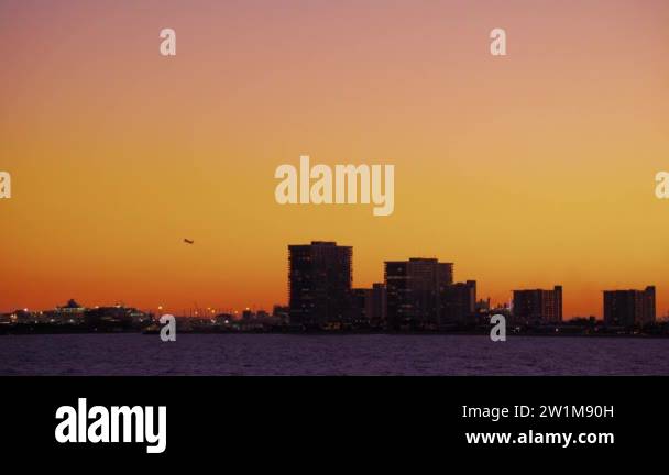 Airplane takes off above city buildings on sunset orange sky in Fort ...