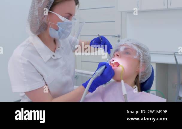 Dentist cleaning brushing and polishing womans teeth uses drill in ...