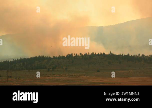 Firefighting helicopter dropping water mostly obscured in heavy smoke ...