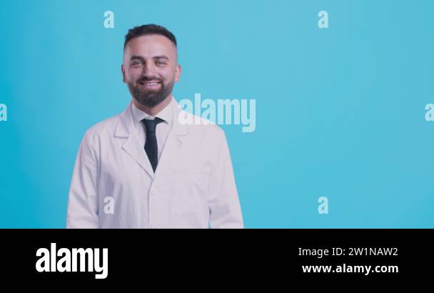 Studio portrait of friendly medical doctor, blue background, free space ...