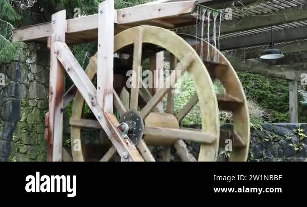 Water wheel of an old-fashioned mill rotating under the pressure of the ...