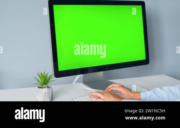Woman typing on a computer keyboard, monitor with a green screen ...