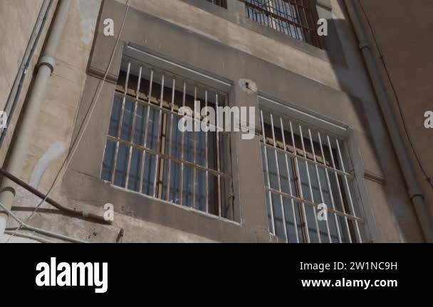 facade of the prison building with spotlight on wall and bars on ...