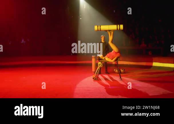 Woman lying rotates the cylinder with her legs on the circus stage ...