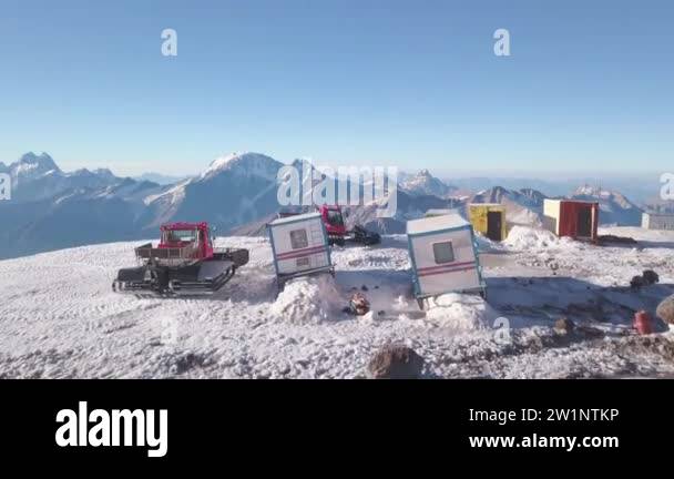 Snowmobiles and houses in snowy mountains. Clip. Top view of snowcats ...