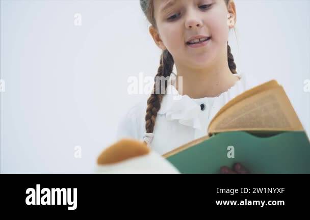 Cute little girl sitting with her legs curled up, reading fairy-tale ...