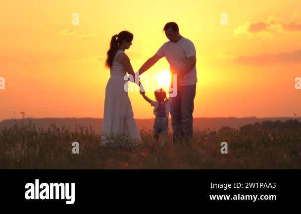 young mom, dad, with a healthy little daughter are dancing in a circle ...