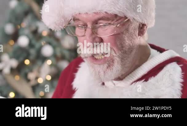 Extreme close-up of Santa Clauss face in eyeglasses making displeased ...