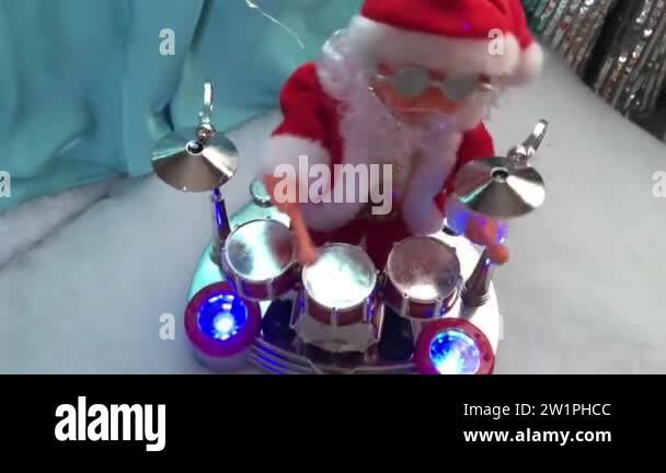 Little red Santa Claus is rocking and drumming on a red drumset with hi ...
