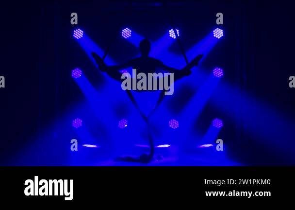 Female aerial gymnast performing rotate and twine on a red silk ...