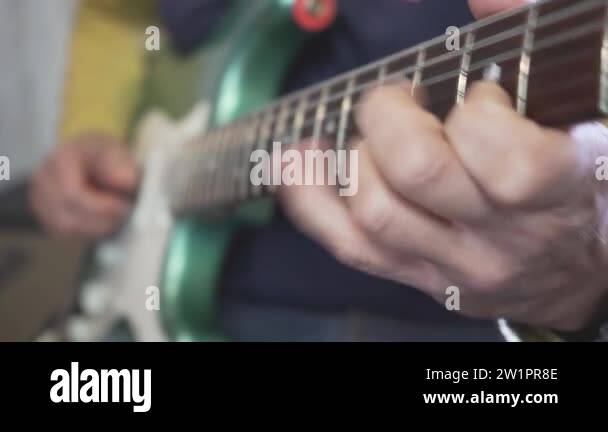 A close-up of a guitar master's hand sliding on the neck playing chords ...