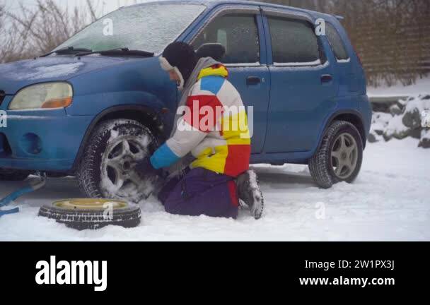 Winter, falling snow. Man on the road have troubles with his car. He is ...