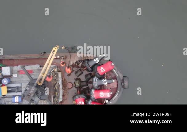A barge loaded with scrap metal and waste floating on a water surface ...