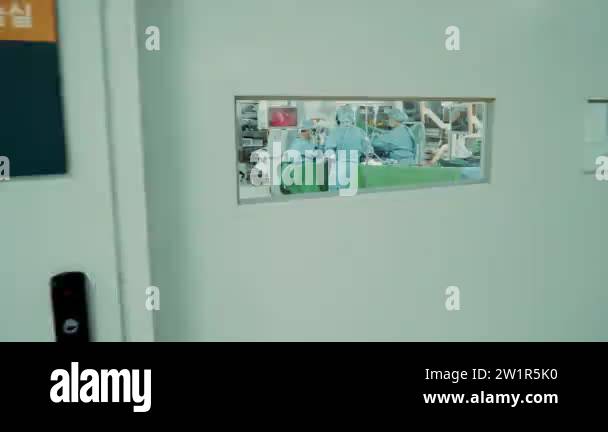 Operating room with doctors during surgery with view through window in ...