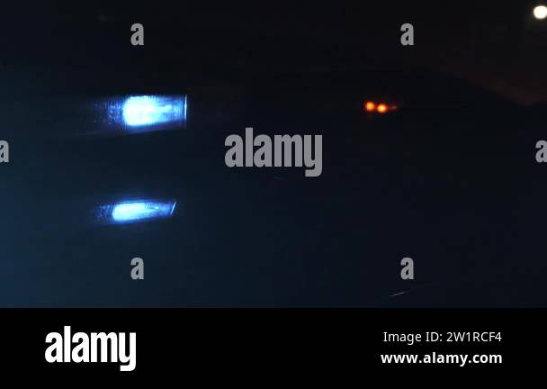 Multiple police cars patrol the night streets, close up on flashing ...