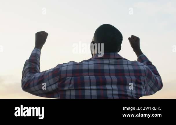 Black man rising hands up showing success gesture, winner, magic hour ...