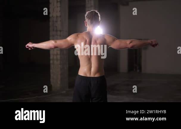 Strong bodybuilder posing backside after training with spotlight lens ...