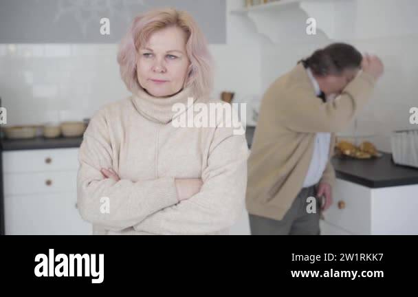 Scared senior Caucasian woman with crossed hands listening to angry man ...