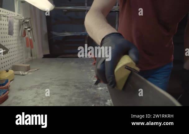 Male worker of ski service workshop doing sharpening and repair of skis ...