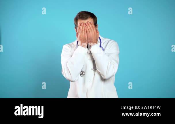 Young doctor man in professional medical white coat covers his face ...