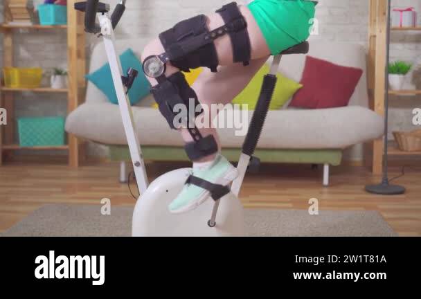young woman knee bend orthosis knee brace after injury on a stationary ...