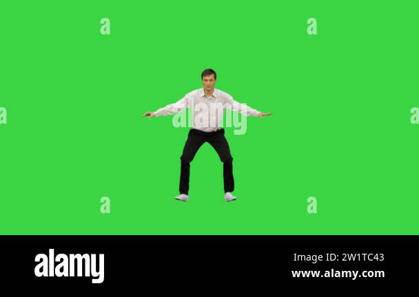 Young man in white shirt dancing a modern dance with bent arms on a ...