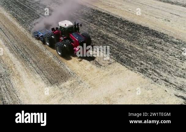 Shooting from drone flying over tractor with harrow system plowing ...