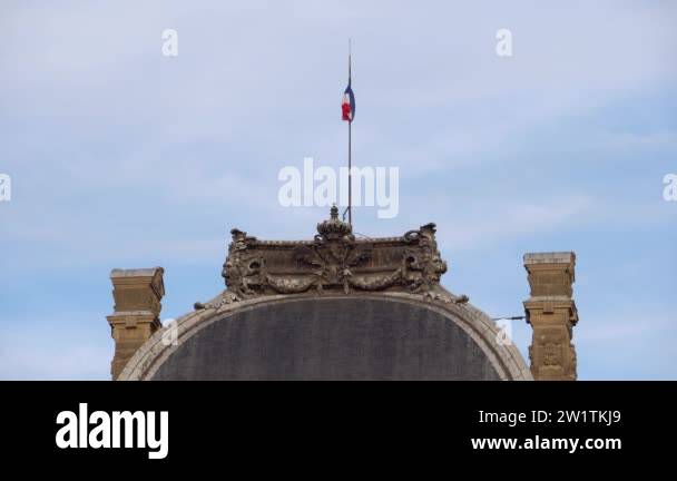 Flag of France waving in the wind. Flagpole is installed on roof Louvre ...