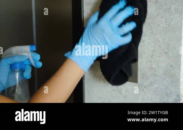 Hands in blue rubber gloves cleaning and disinfecting elevator buttons ...