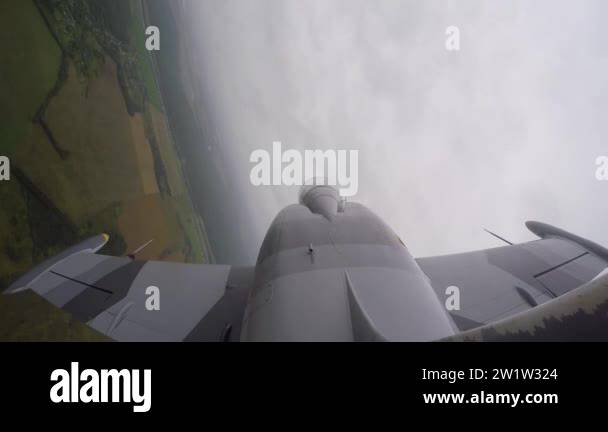 A gray blue combat plane fly over field and rolls to the left. A ...